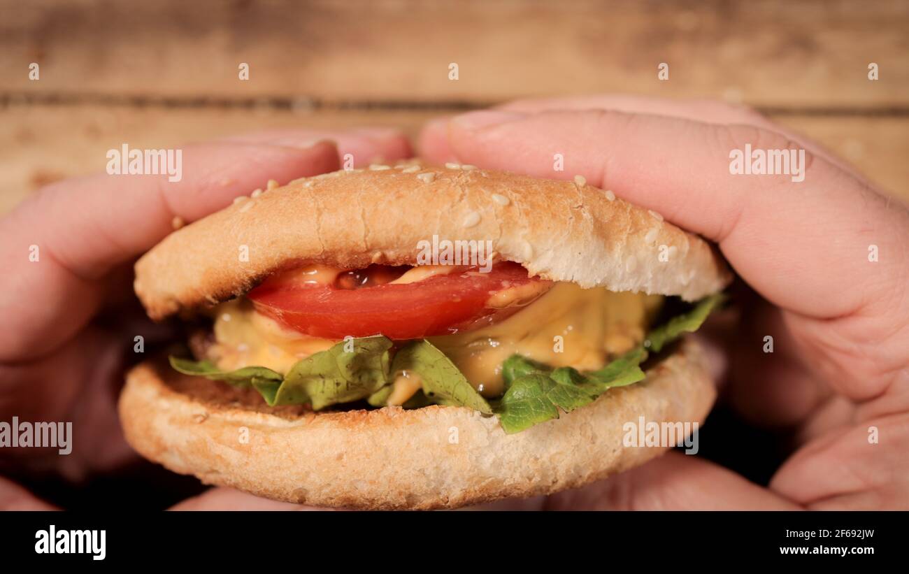 Holding a freshly grilled cheeseburger - ready to eat Stock Photo - Alamy