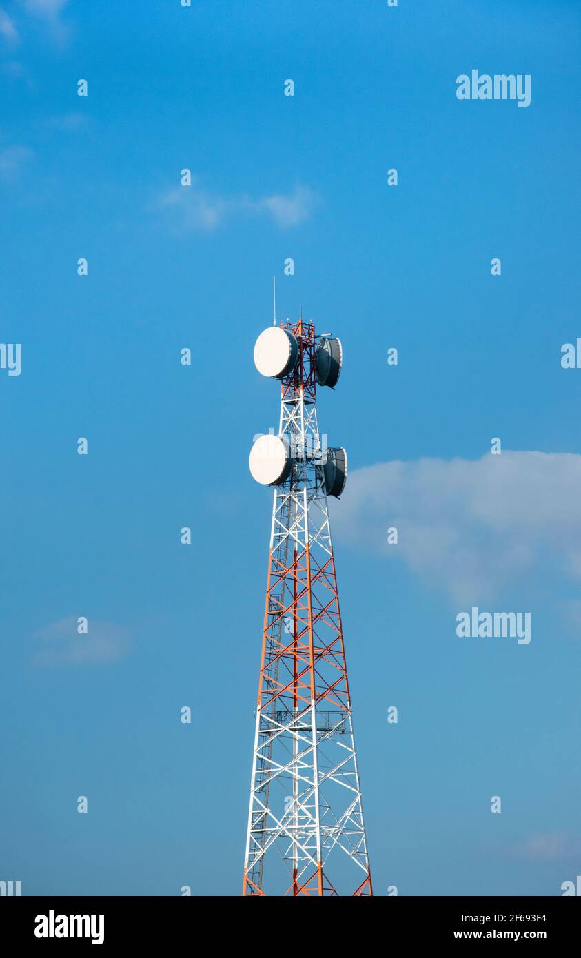 Telecommunication tower with antennas on a background of blue sky and clouds. Smart antennas ...