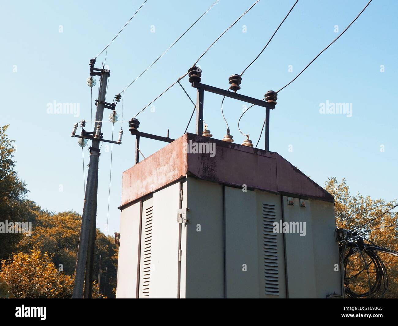 Top of a transformer booth with power lines against background of blue ...