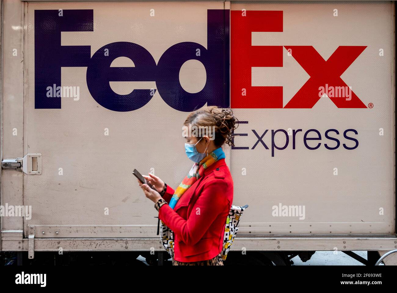 A pedestrian walks past the American FedEx Express delivery truck seen ...