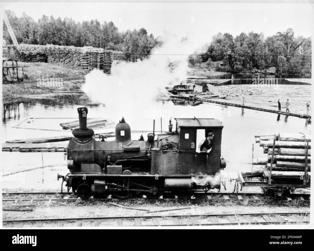 Steam locomotive at the water bridge connected with timber car. Timber ...