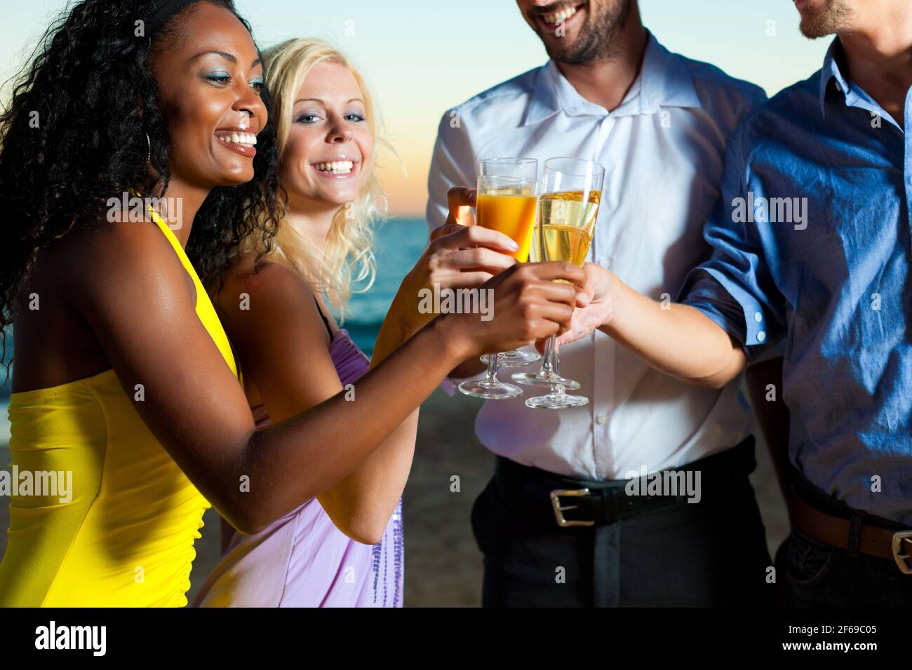 People (two couples) on the beach having a party, drinking and having a ...