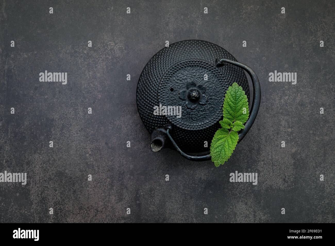Black cast iron tea pot with herbal tea set up on dark stone background ...