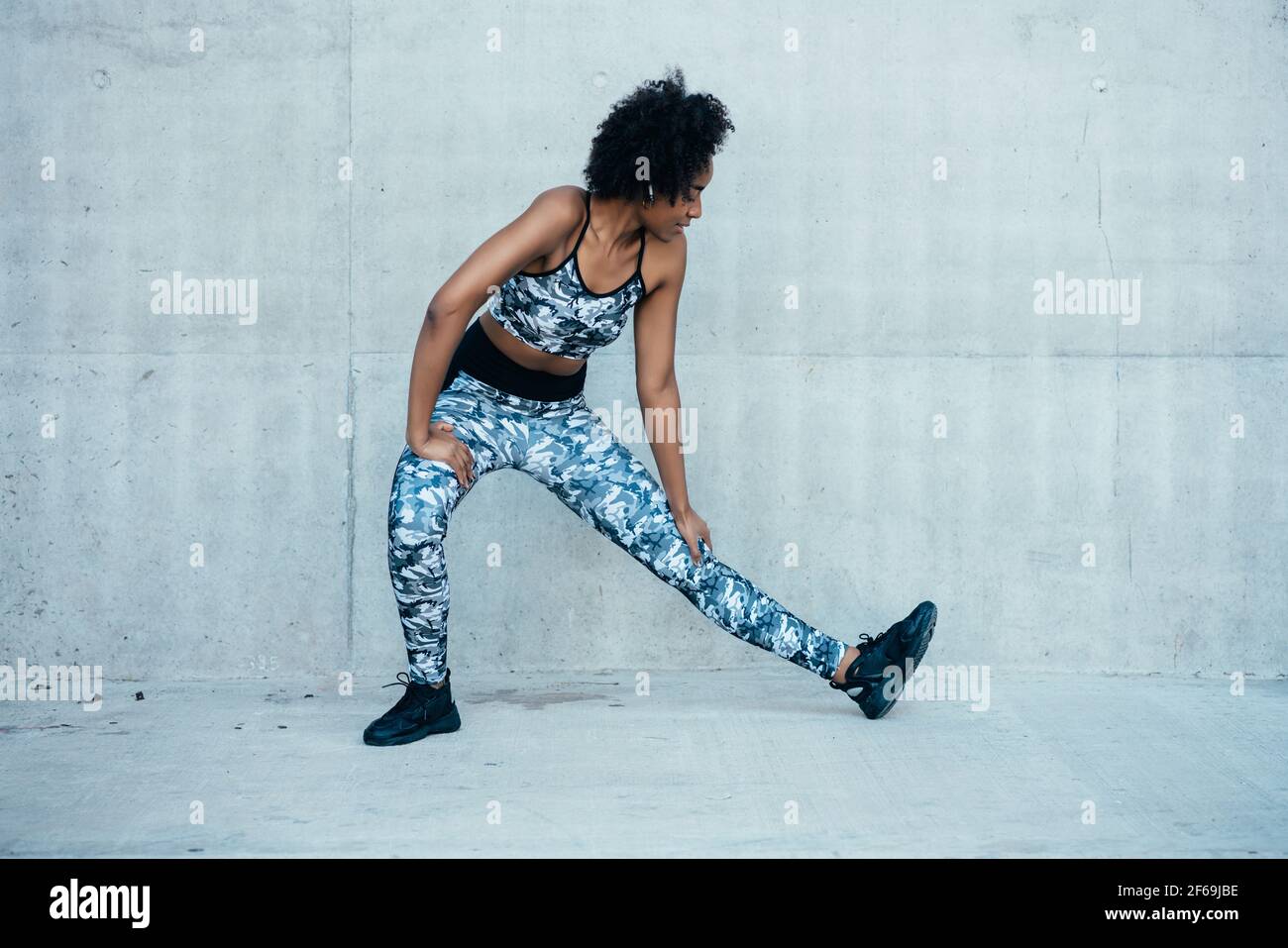 Afro athletic woman stretching legs before exercise Stock Photo - Alamy