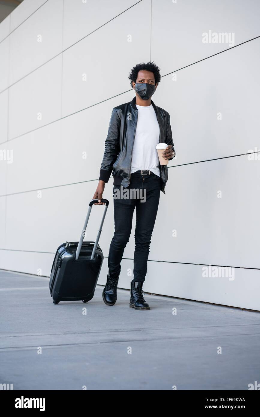 Tourist man carrying suitcase while walking outdoors Stock Photo - Alamy