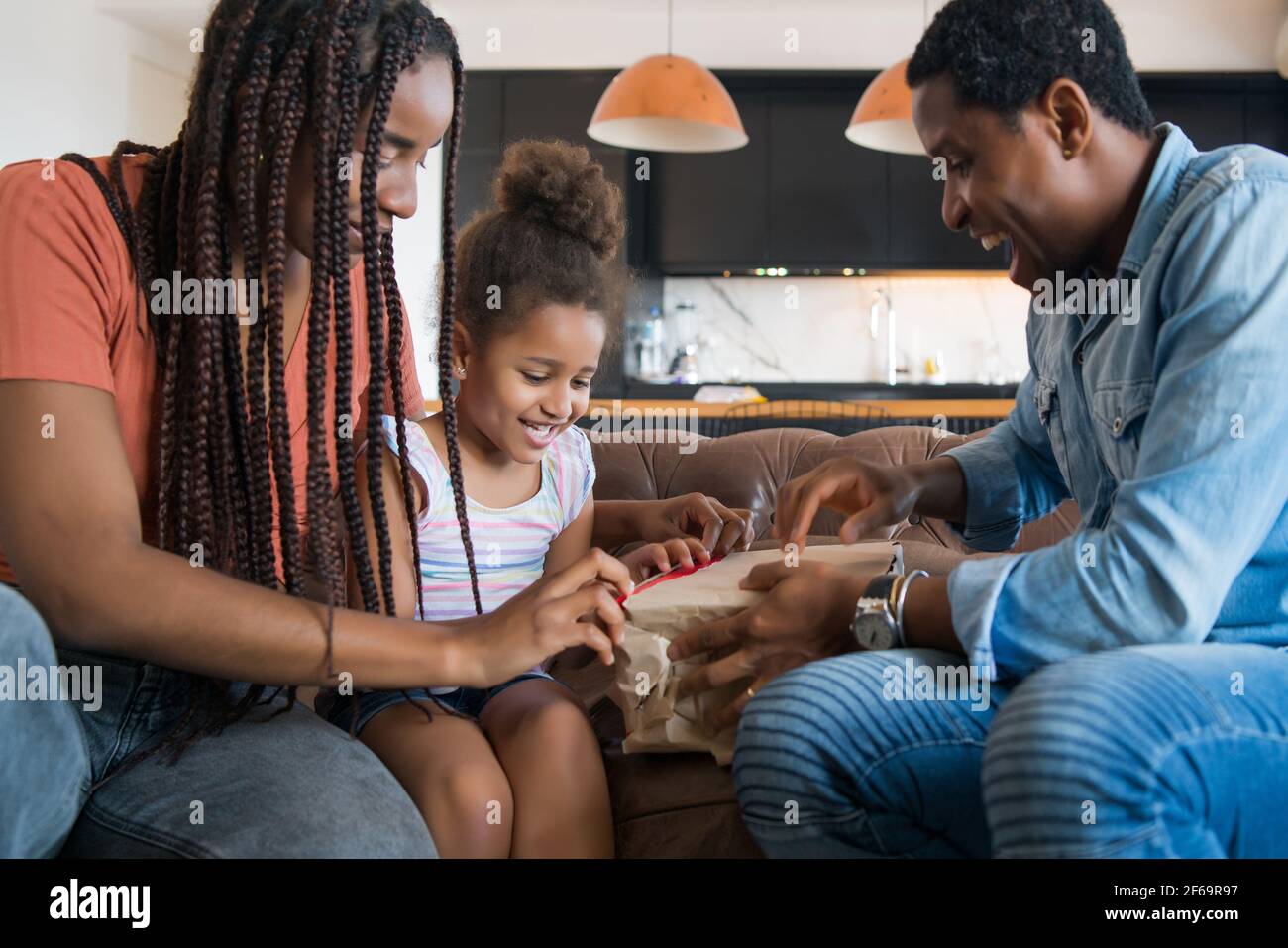 Little girl receiving gift from her parents Stock Photo - Alamy
