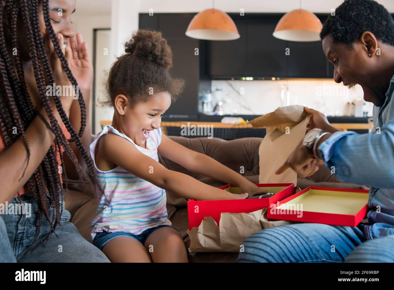 Little girl receiving gift from her parents Stock Photo - Alamy