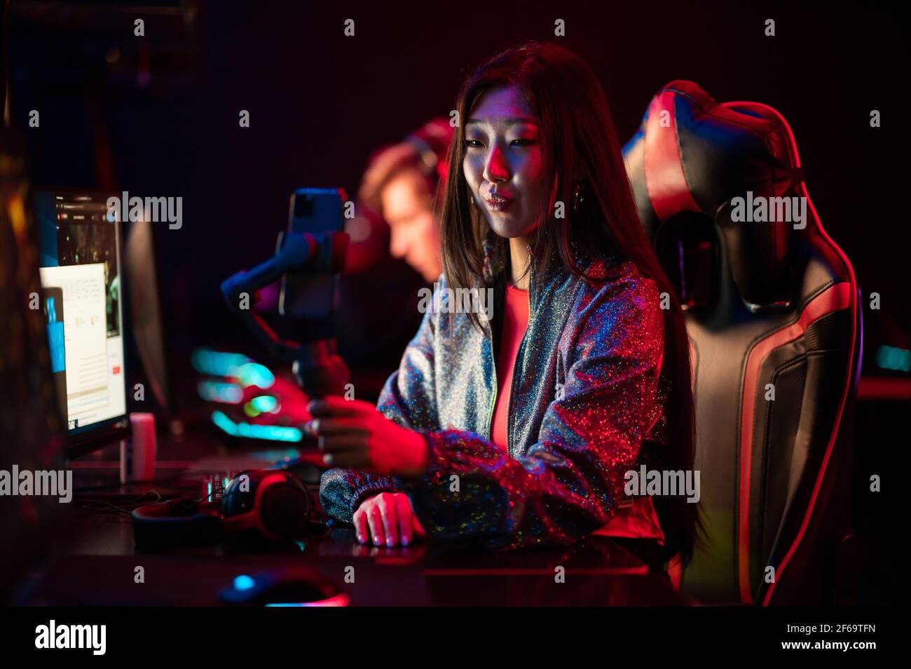 A young beautiful asian girl is broadcasting online on a smartphone ...