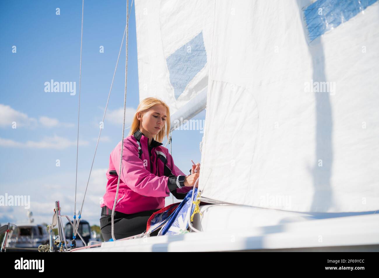 Young athletic girl in sports clothes on a yacht in the dock is ready ...