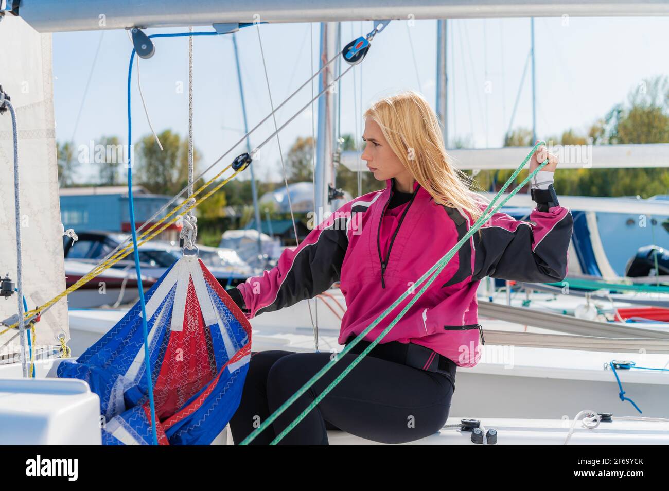 Young athletic girl in sports clothes on a yacht in the dock is ready ...