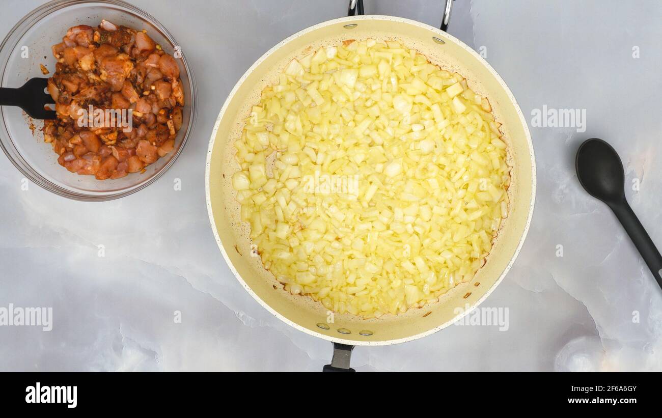 Fried chopped onion on frying pan, close up view from above. Sour cream ...