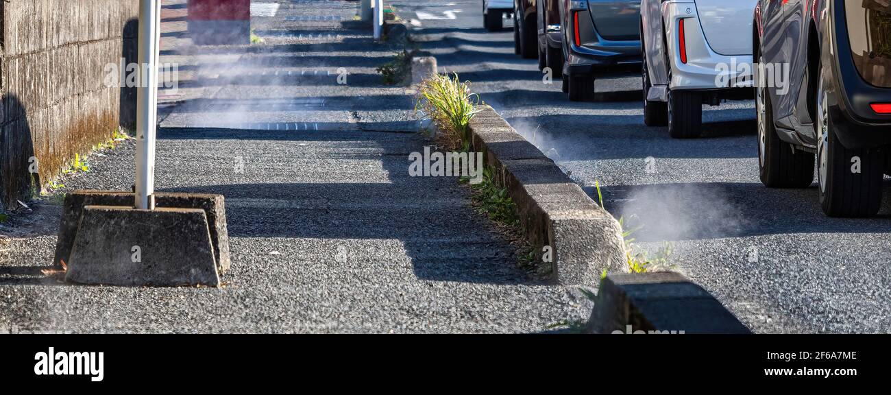 Steam arises from metal grates in the road and pavement, because of ...