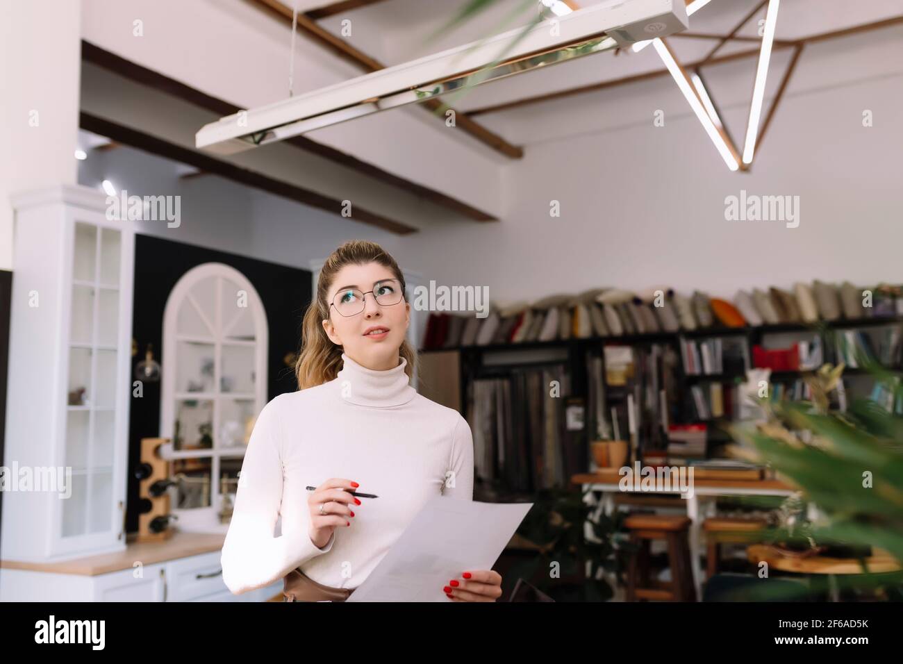 An interior designer is working on a new project, woman holding paper ...