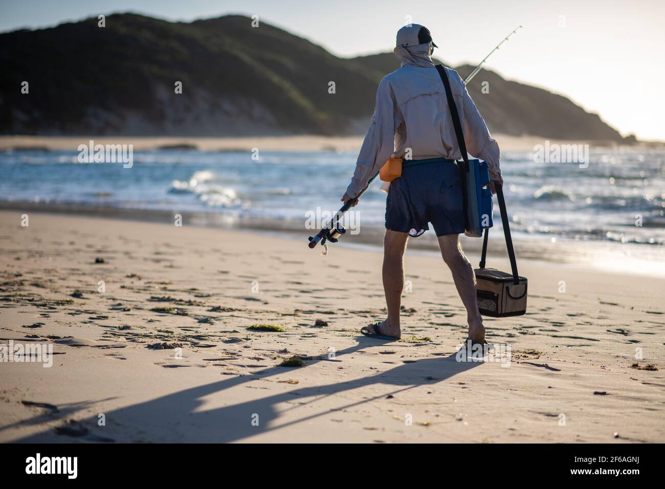 Man walking with his fishing gear along coast Stock Photo - Alamy