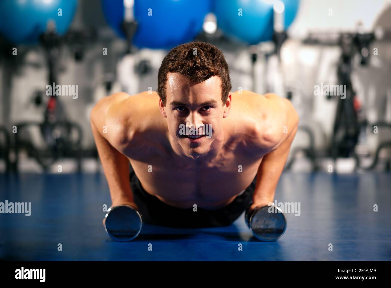 Very strong and muscular man exercising by doing pushups in a gym Stock ...