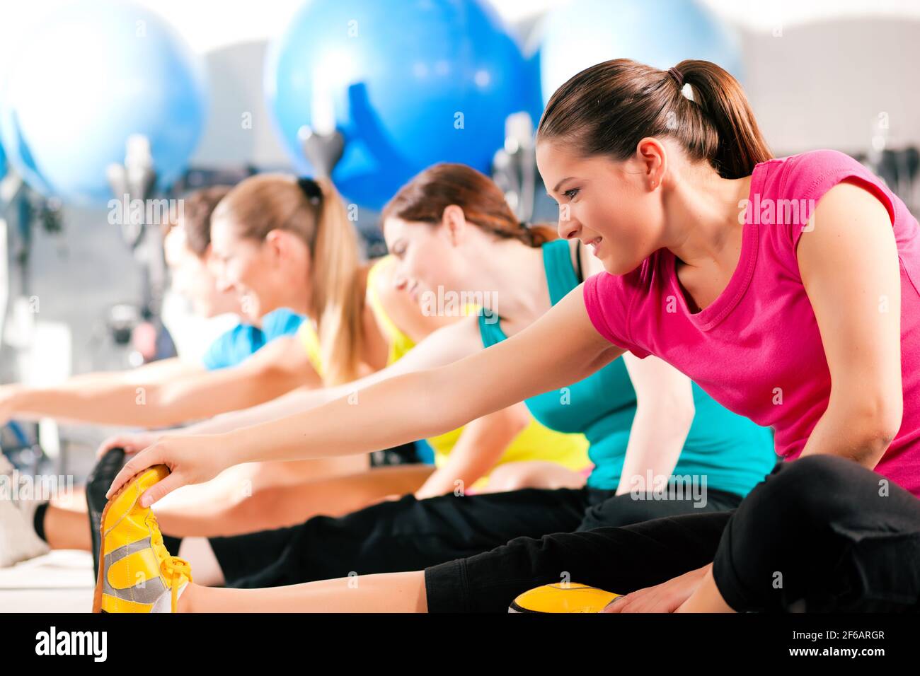 Group of four people in colorful cloths in a gym doing aerobics or ...