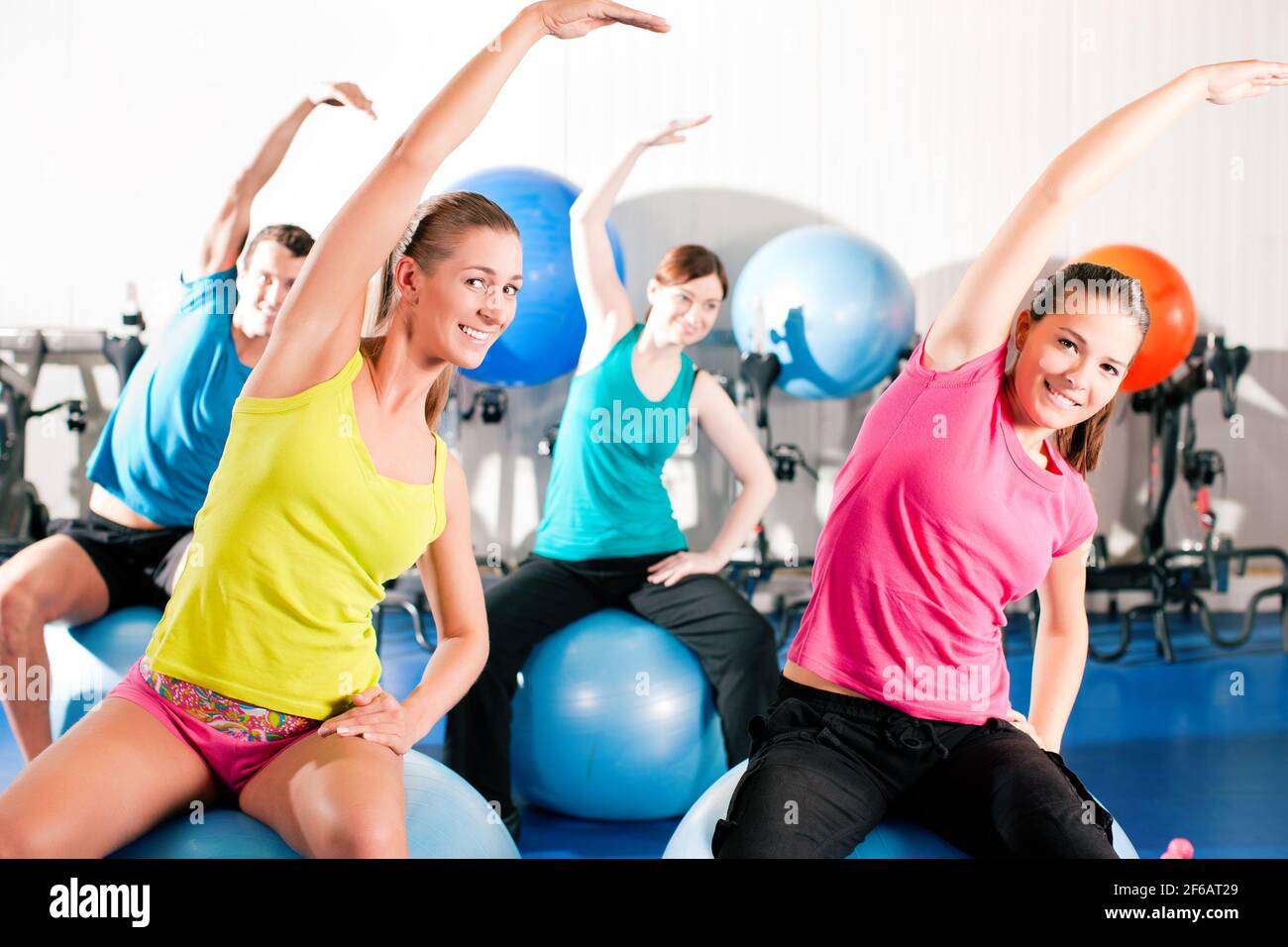 Four people - man and women - in the gym doing gymnastics on an ...