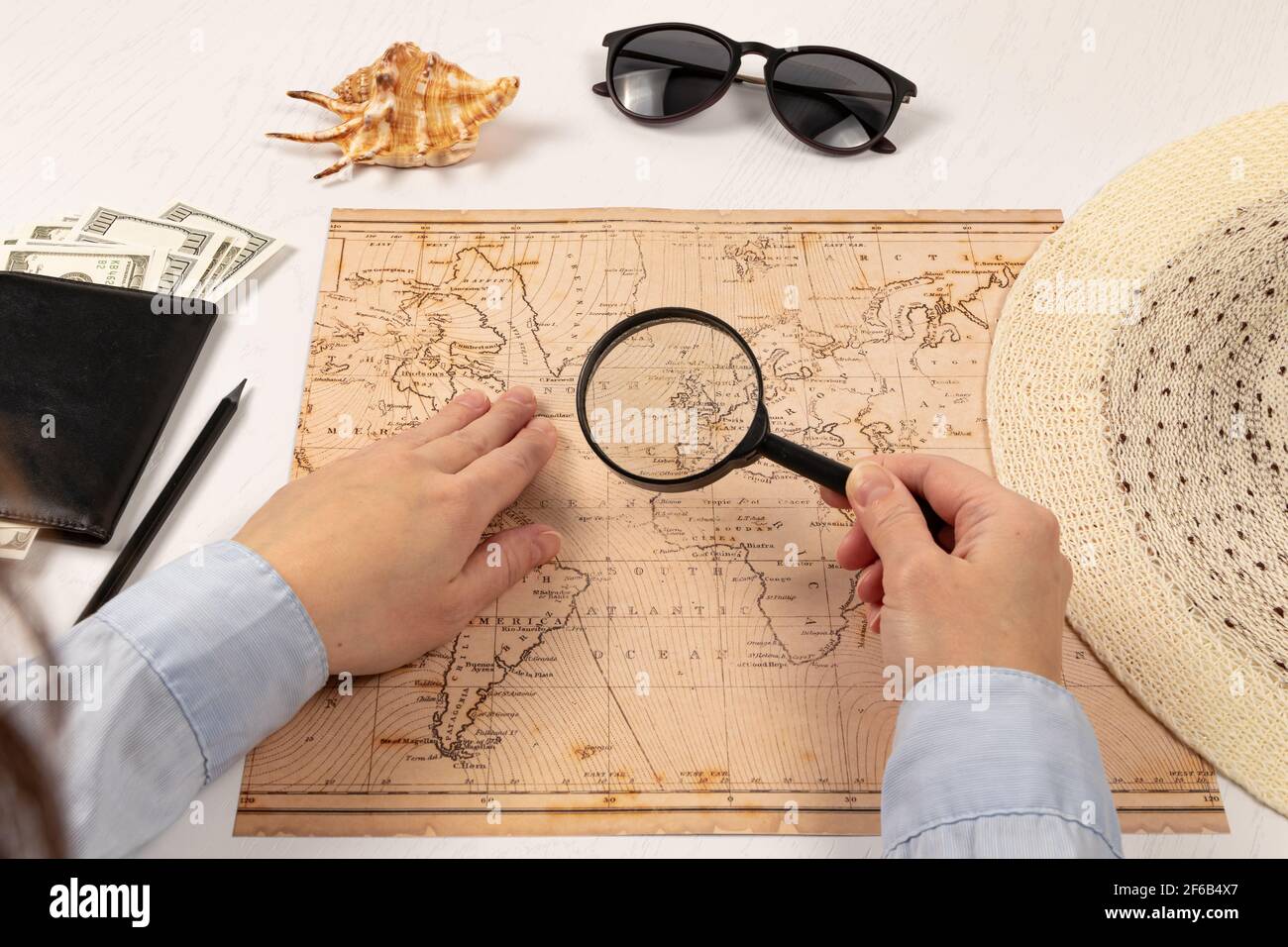 female hands hold a magnifying glass over the world map. on a white ...