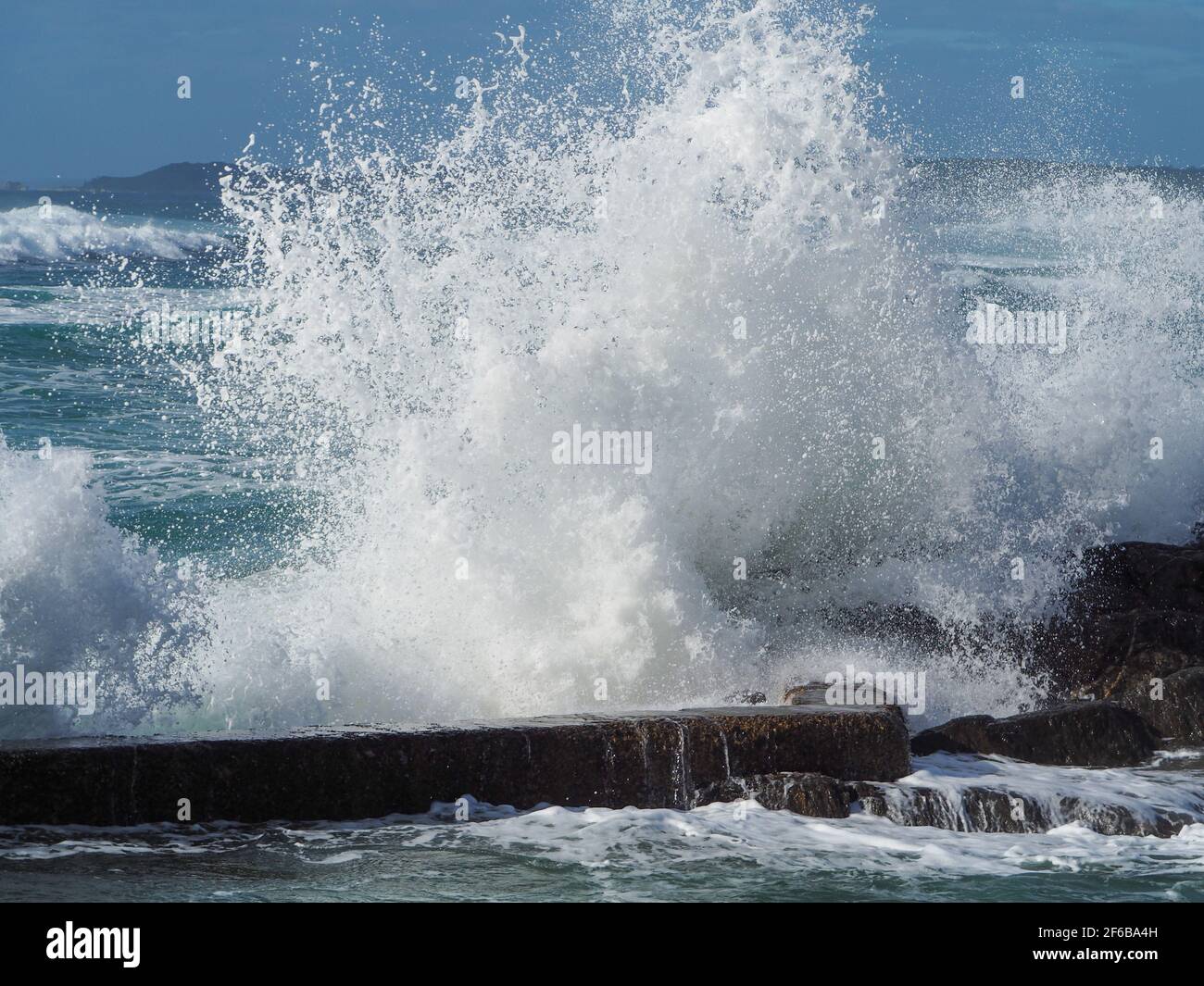 Closeup to ocean waves smashing into and crashing up over the wall of ...