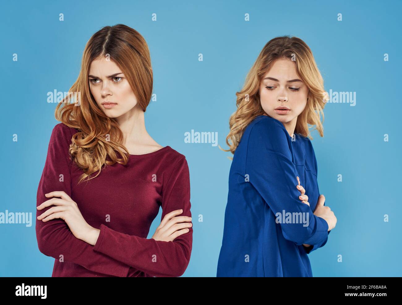 two girlfriends in dress conflict emotions blue background studio Stock ...
