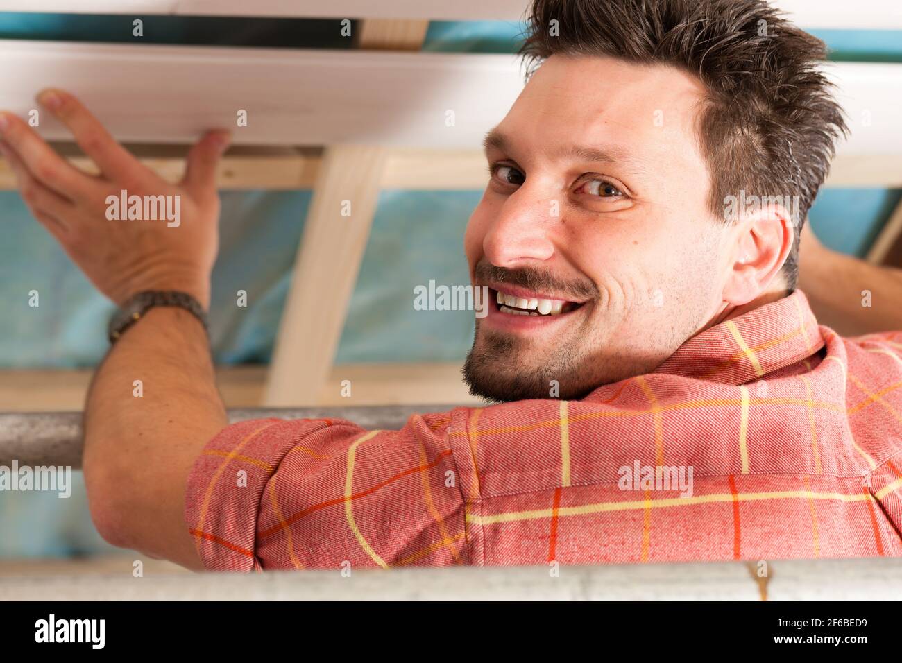 Man doing dry walling, working under a roof slope Stock Photo - Alamy