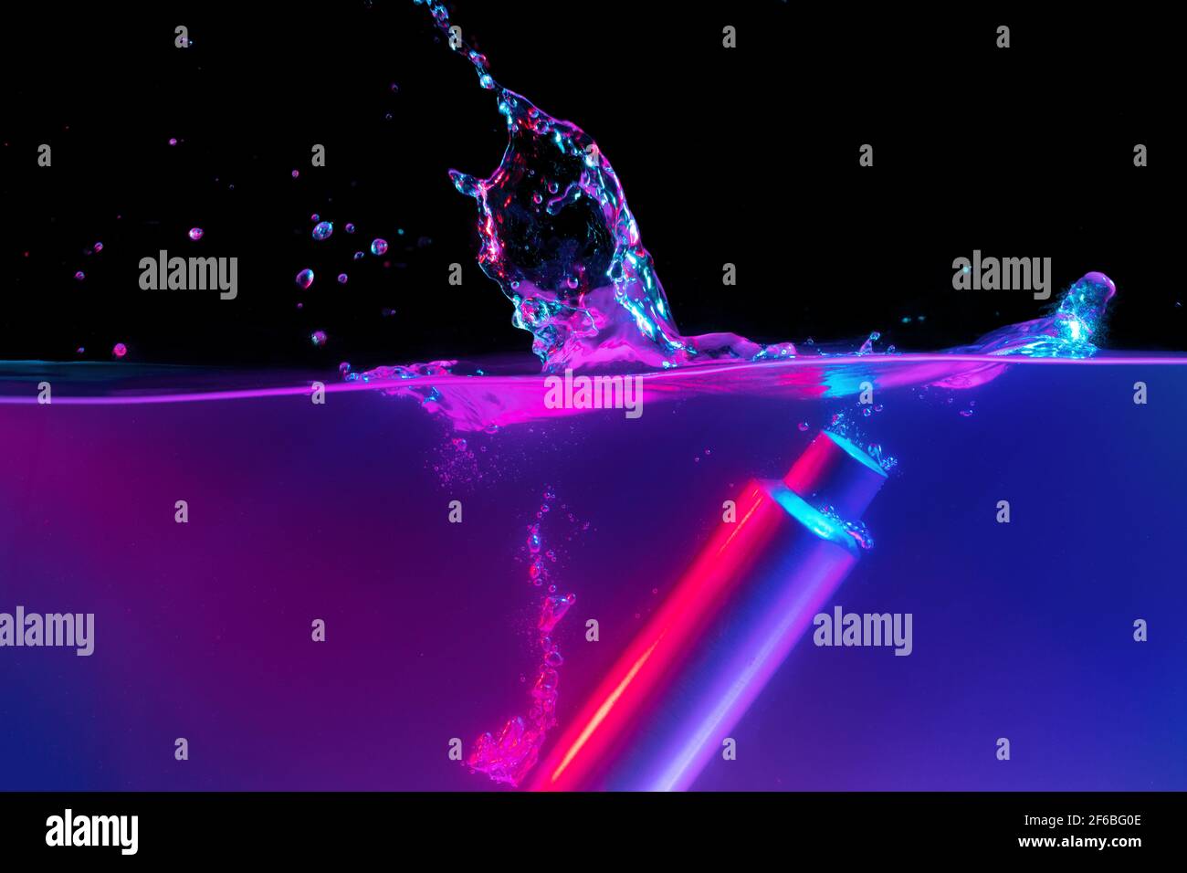Skincare product bottle falling into water against black background in ...