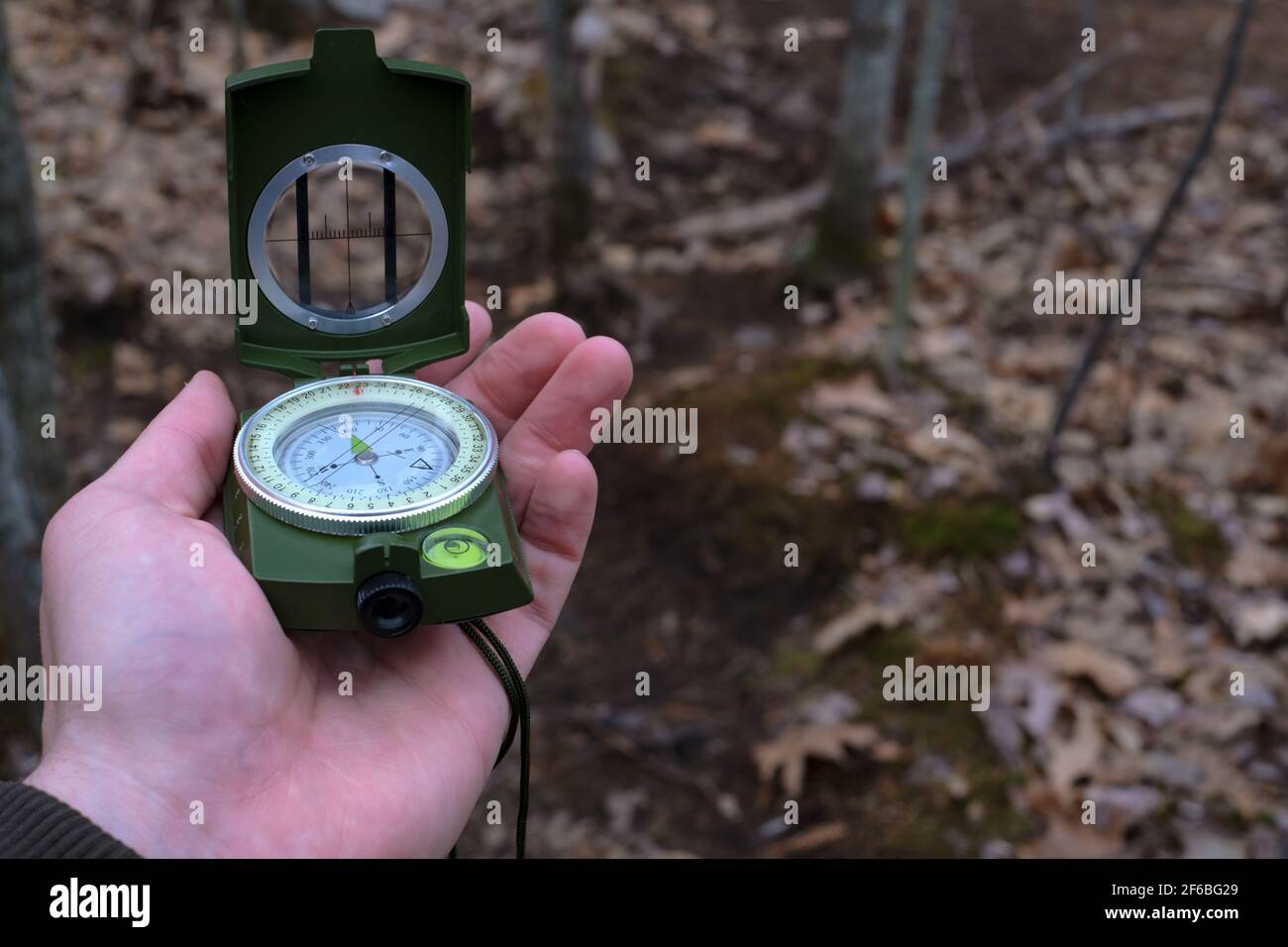 A hand is holding a prismatic compass and raising it for navigational ...