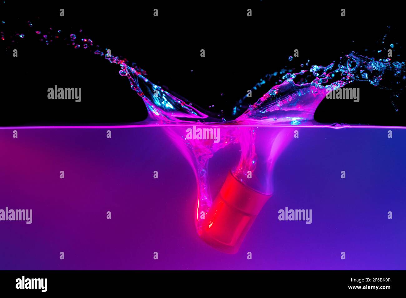 Skincare product bottle falling into water against black background in ...