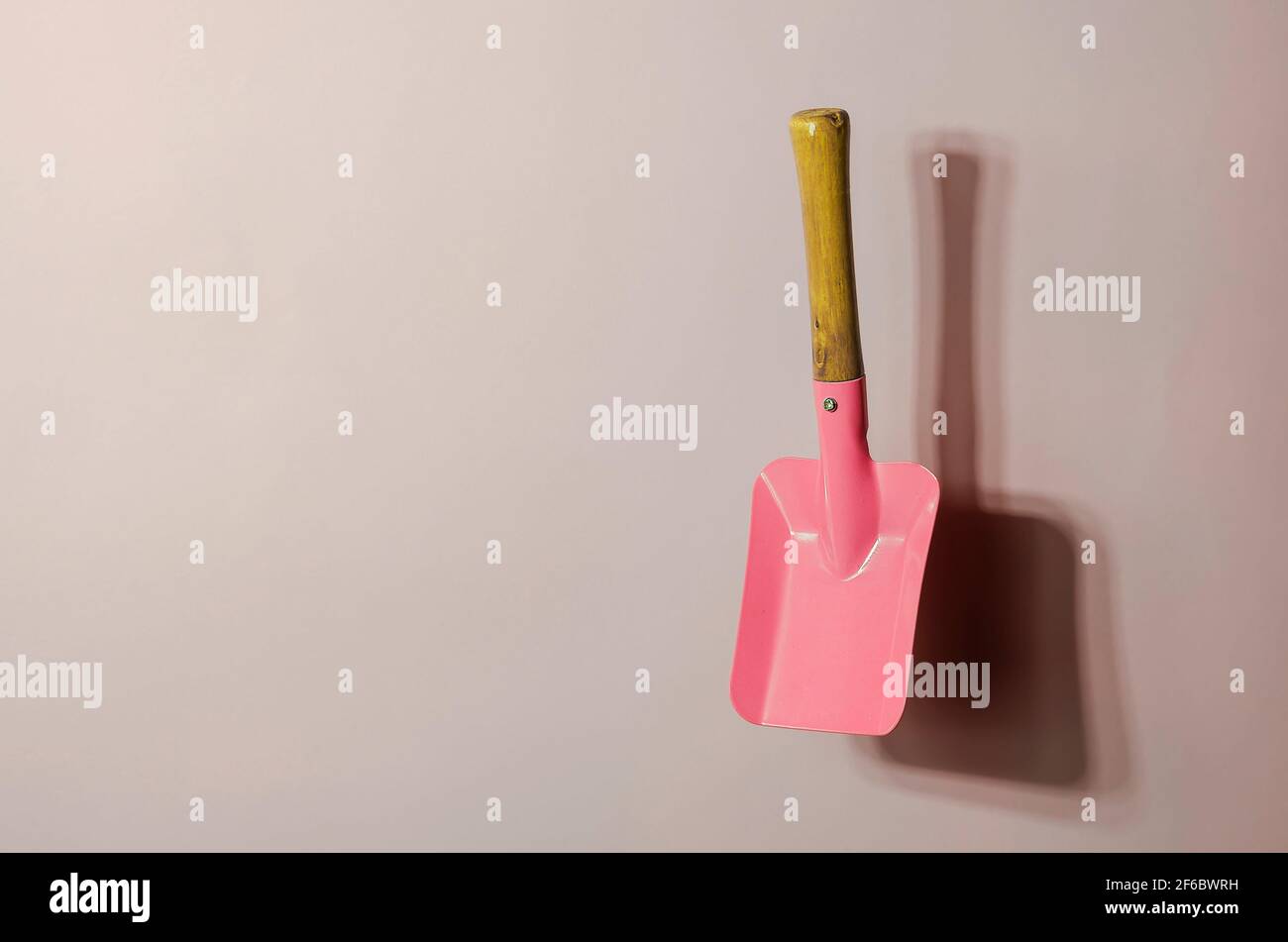 Minimalistic composition with a pink garden shovel on a light gray-pink ...