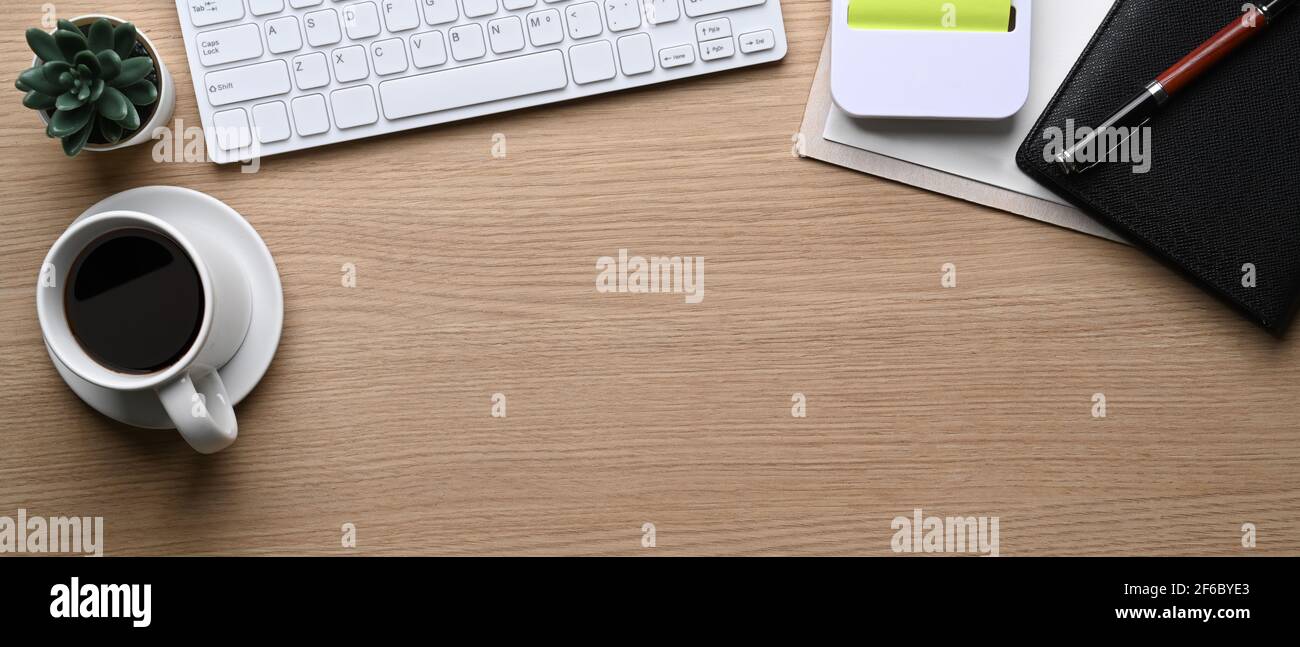 Horizontal image of wooden office desk with keyboard, coffee cup, plant ...