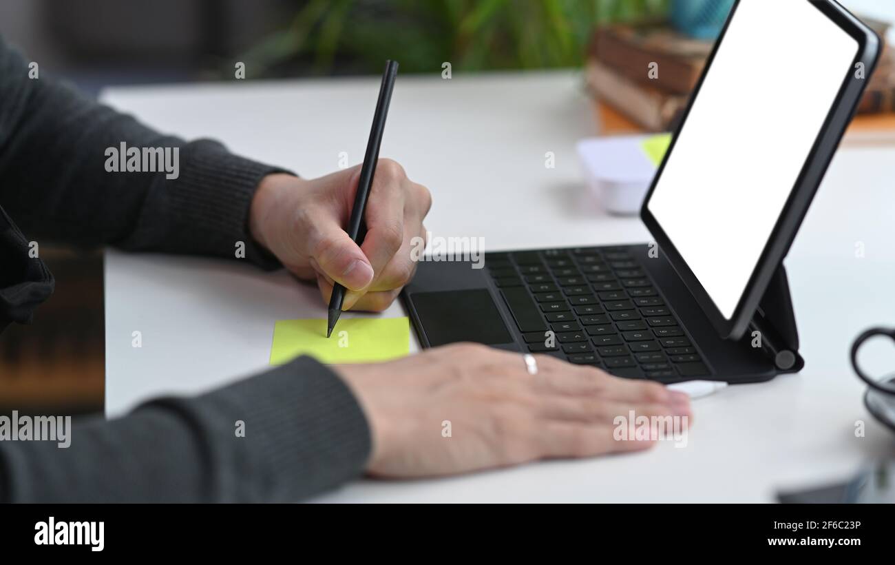 Close up view of man making note on sticky note and working with ...