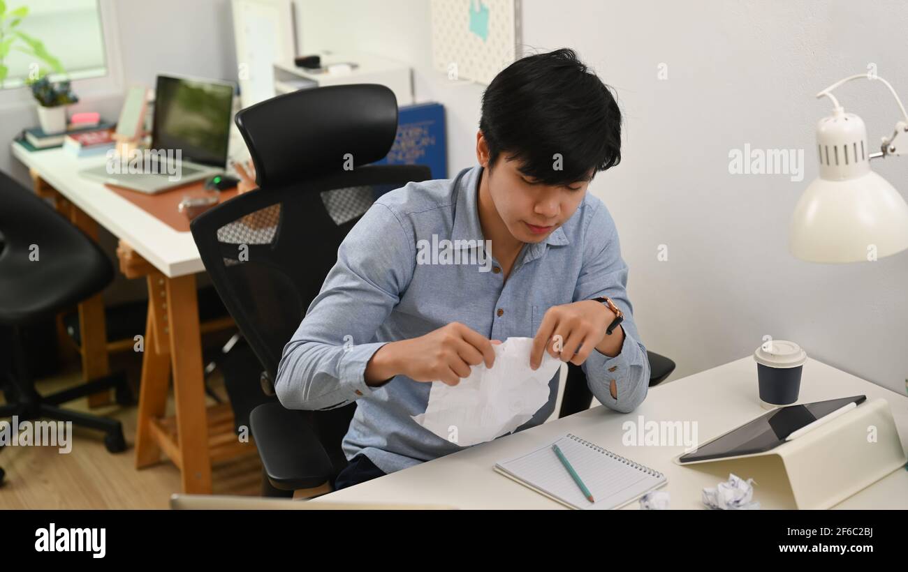 Furious young businessman tearing up a document Stock Photo - Alamy