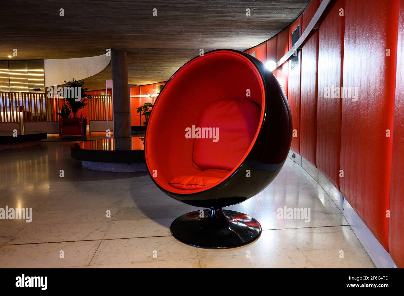 Retro designed red and black seat. Empty sphere shape chair standing in ...