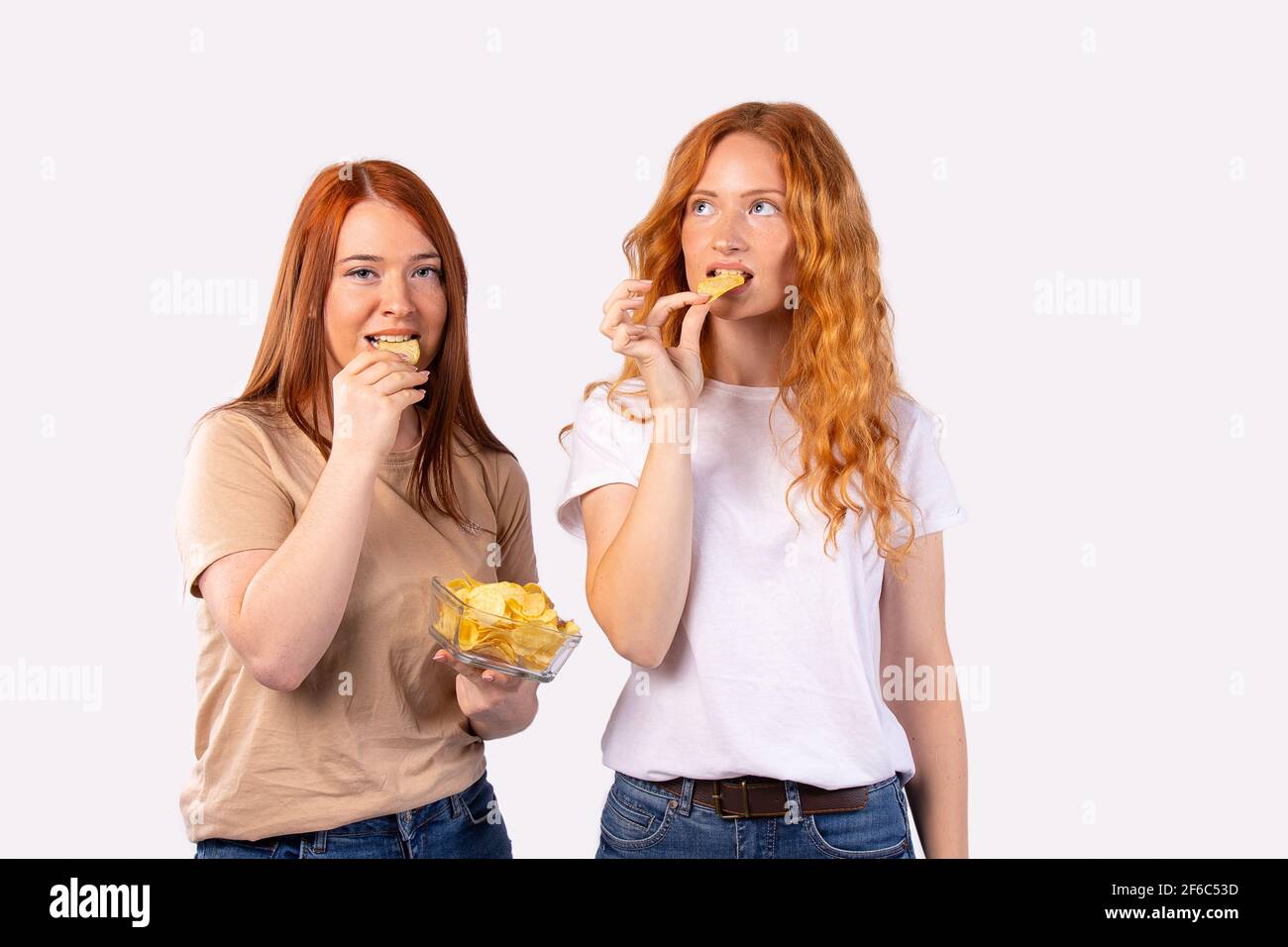 Red-haired girls eat potato chips. A quick snack on a white background ...
