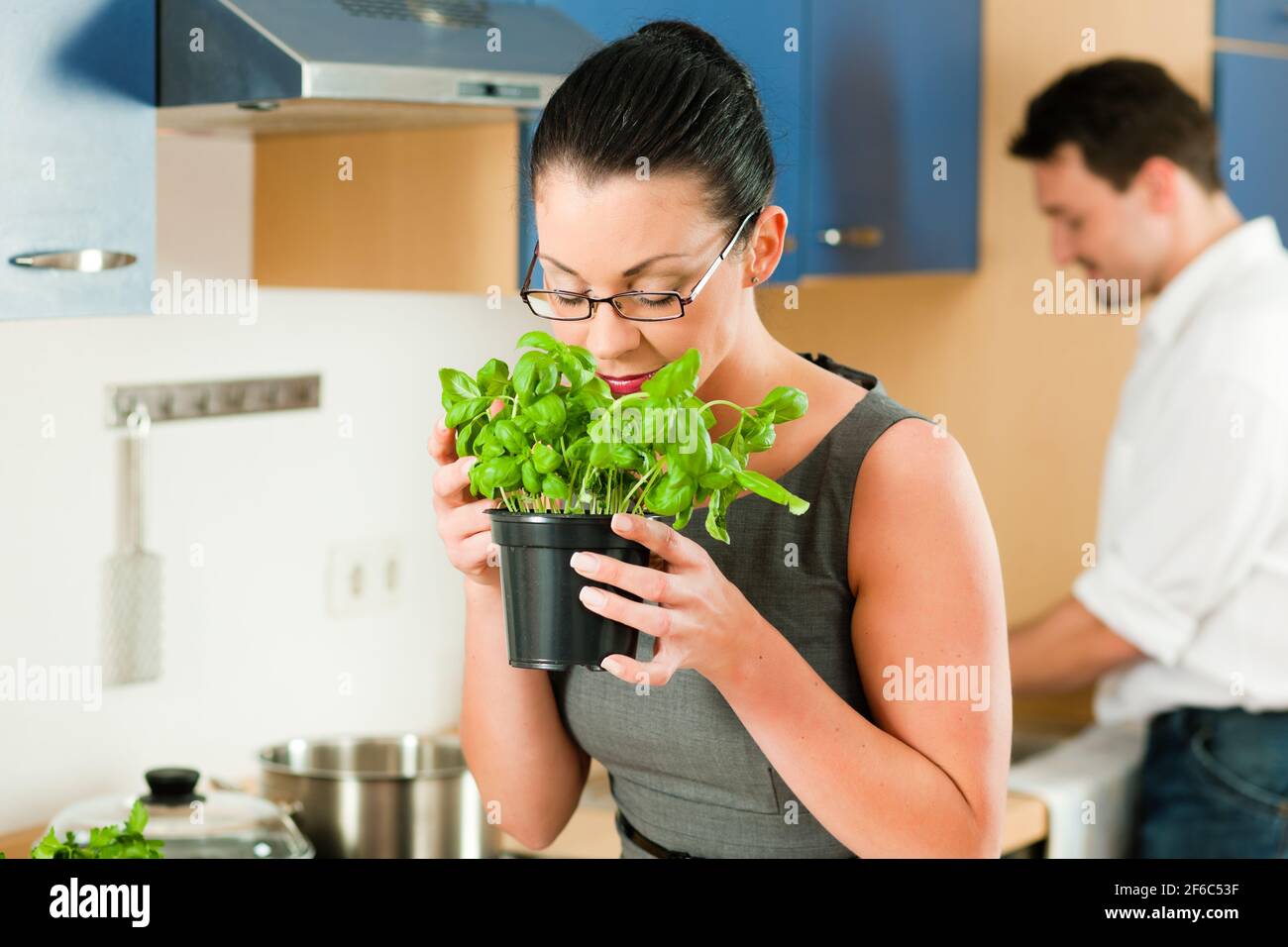 Woman smells the aroma of a basil pot in her kitchen Stock Photo - Alamy