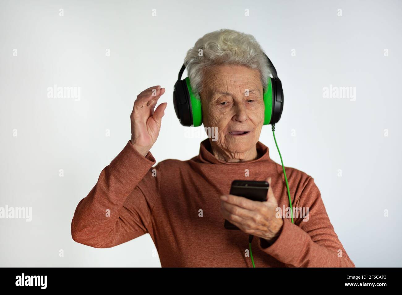 A positive elderly woman listens to music and sings. The older ...