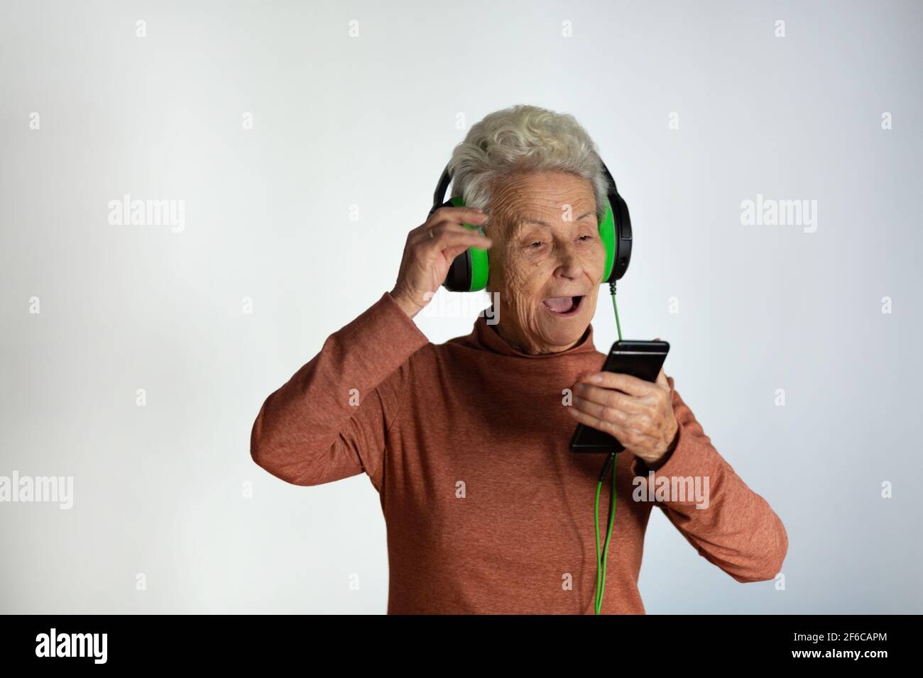 A positive elderly woman listens to music and sings. The older ...