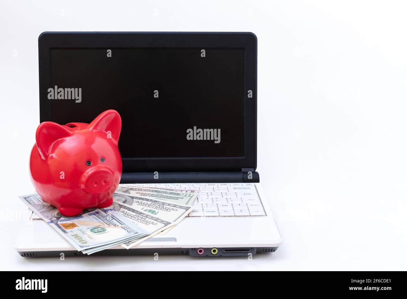 Laptop with blank black screen, red piggy bank and dollars on a white ...