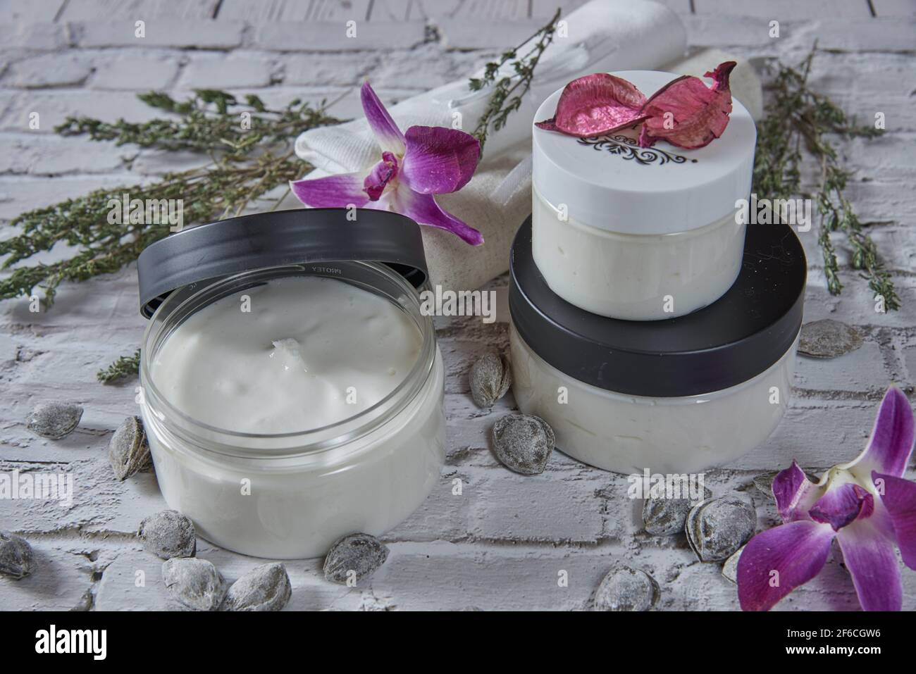Two handmade cream jars decorated with aromatic herbs and apricot pits ...
