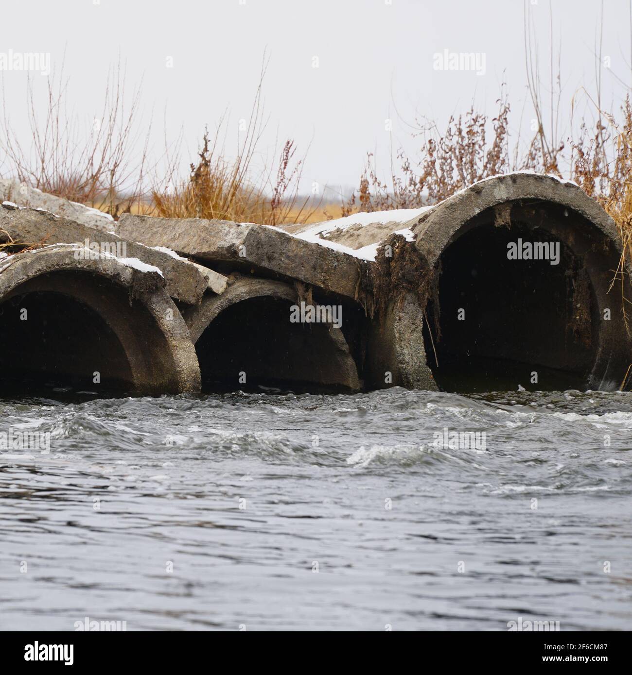 The water on the river flows from large pipes. Dam on the river Stock ...