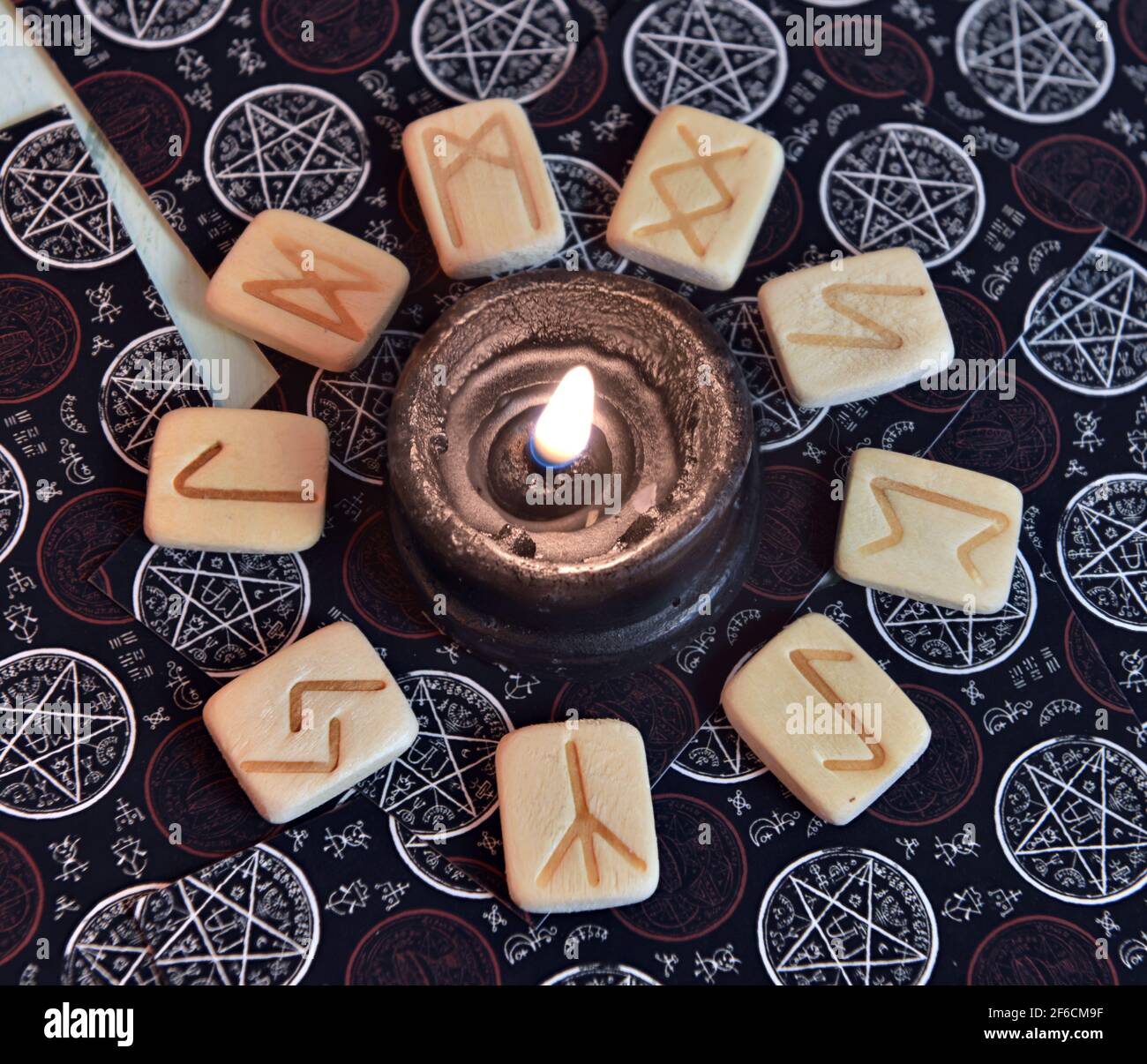 Still life with runes around burning black candle on tarot cards ...