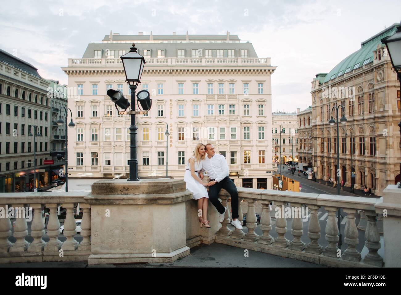 Happy couple sist on the border in front of city. Man and woman in ...
