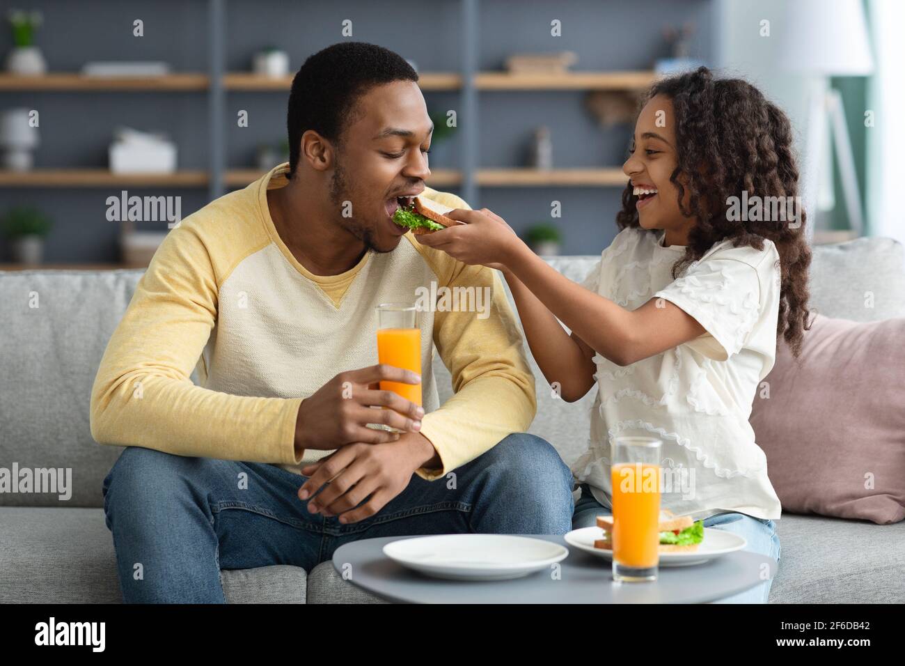 Cute little girl feeding her daddy at home Stock Photo - Alamy