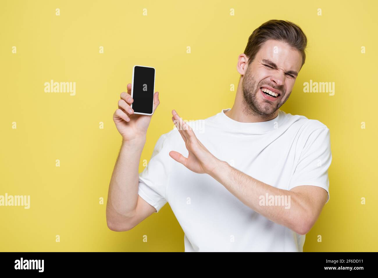 man feeling disgust and showing refuse gesture while holding cellphone ...