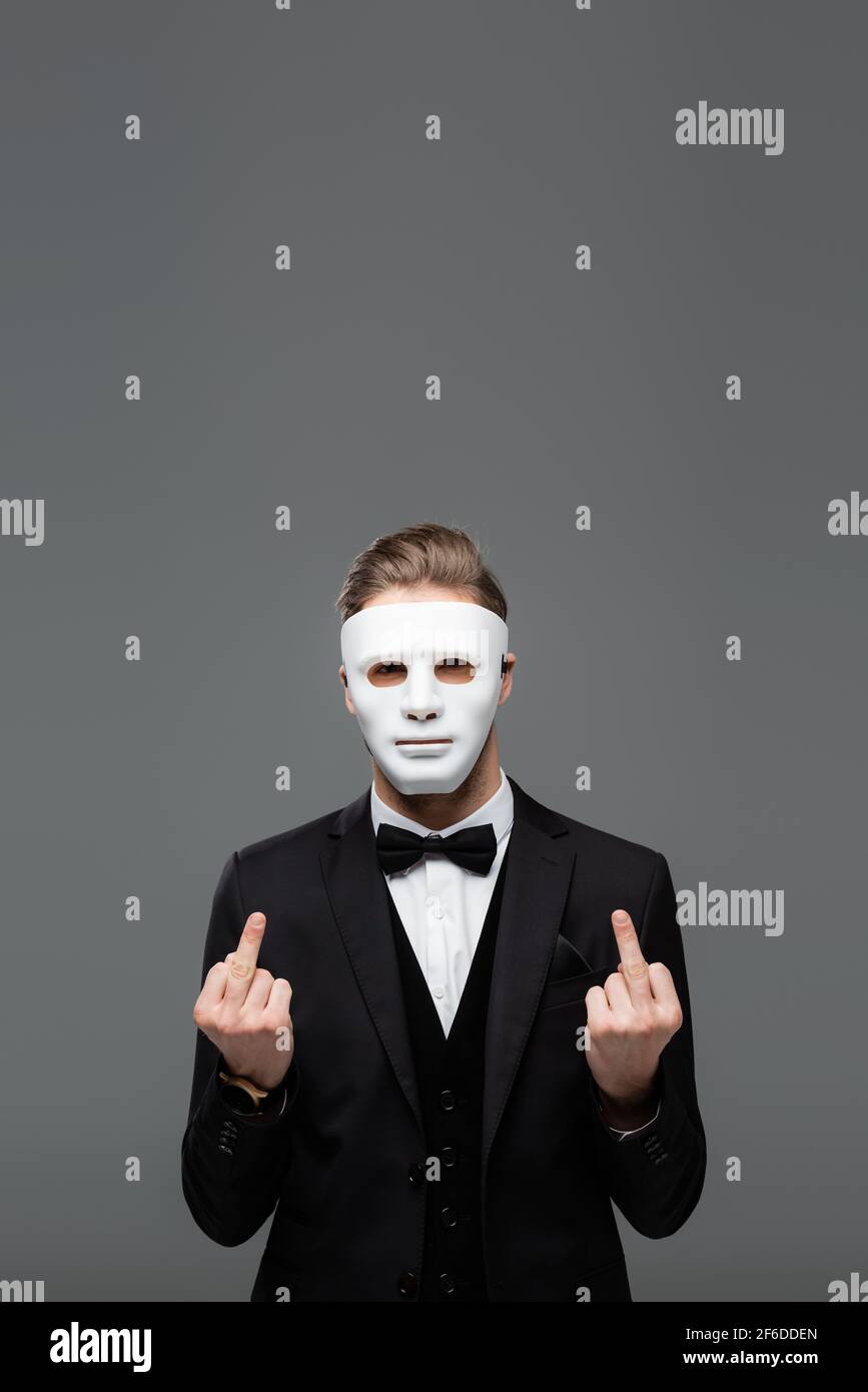 businessman in face mask showing middle fingers isolated on grey Stock ...