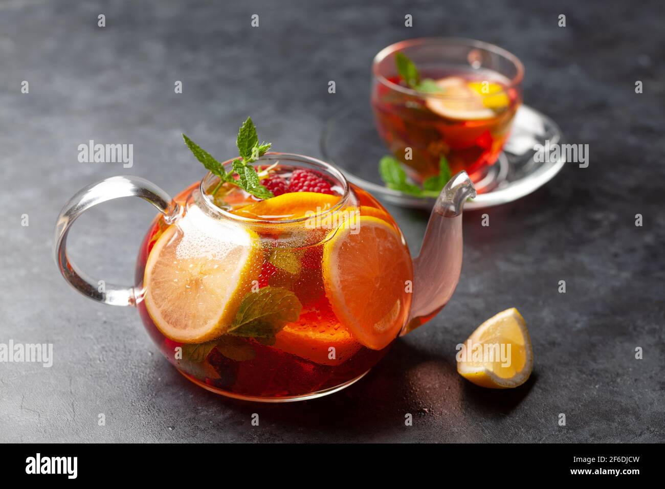 Traditional fruit tea in teapot and glass with lemon, berries and mint ...