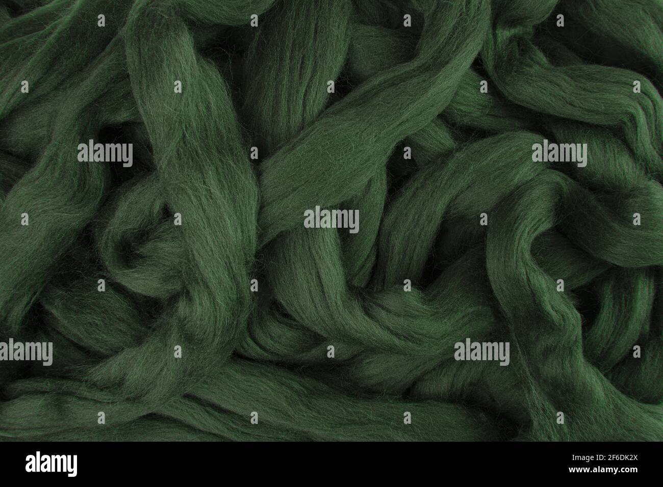 Pretty dark olive green merino wool lying in loose stings ready to be ...