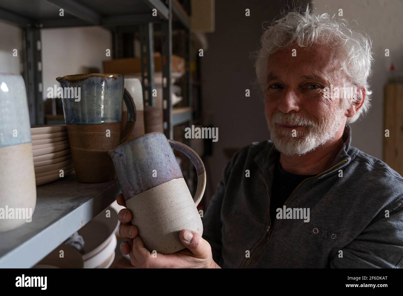 potter craftsman in his studio showing the works displayed on a metal ...