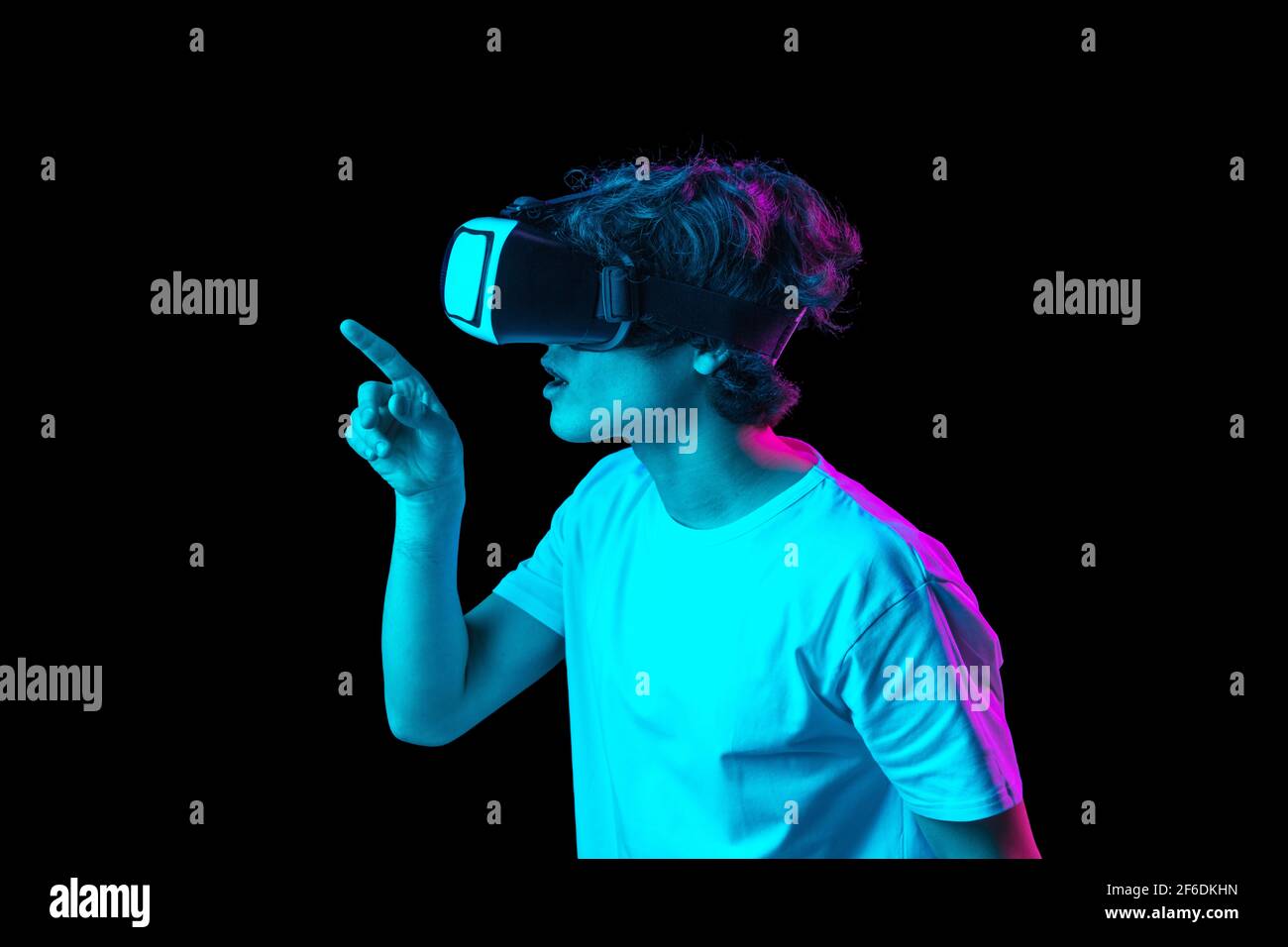 Young man using VR headset isolated over dark background in neon light ...
