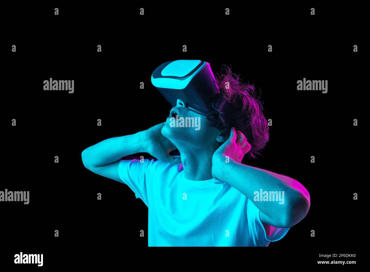 Young man using VR headset isolated over dark background in neon light ...